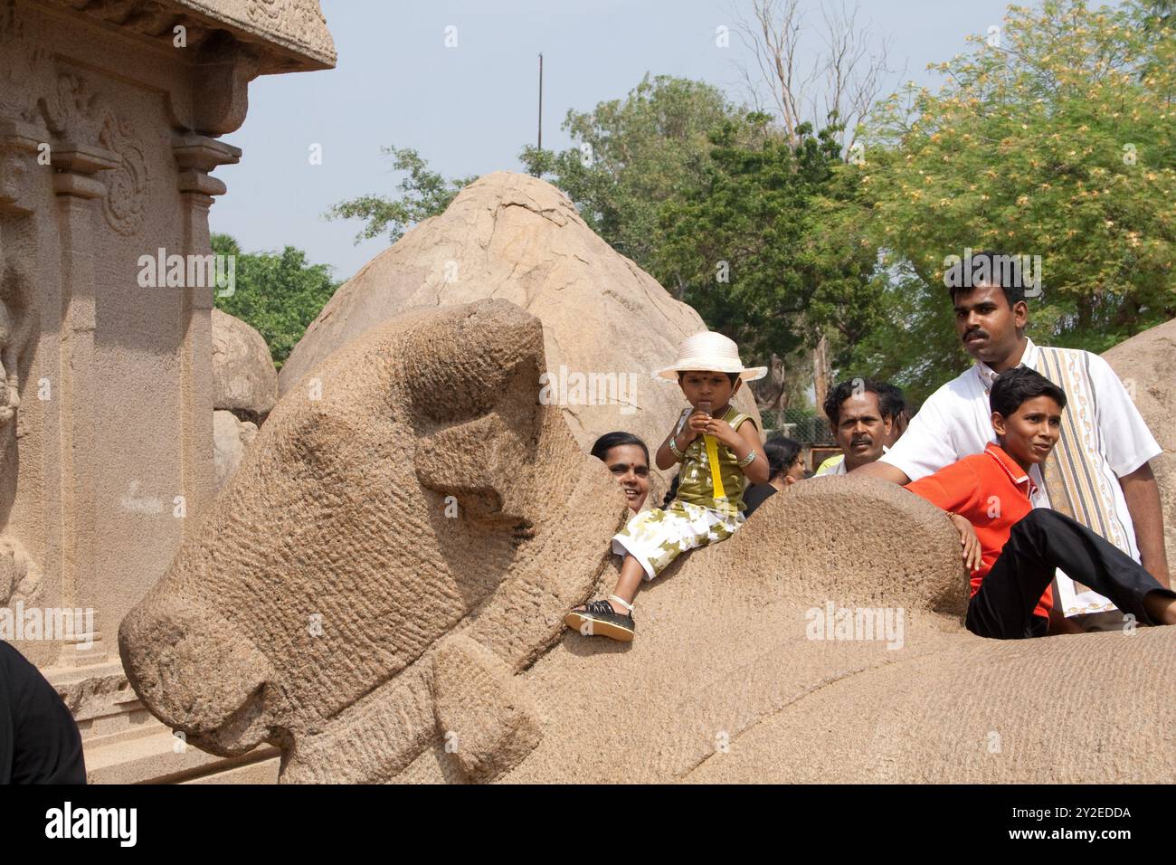 Children enjoy playing on the statue of a cow. Monolithic rock carving ...