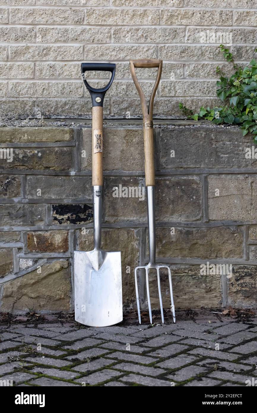 Stainless steel garden spade and fork against a stone wall Stock Photo ...