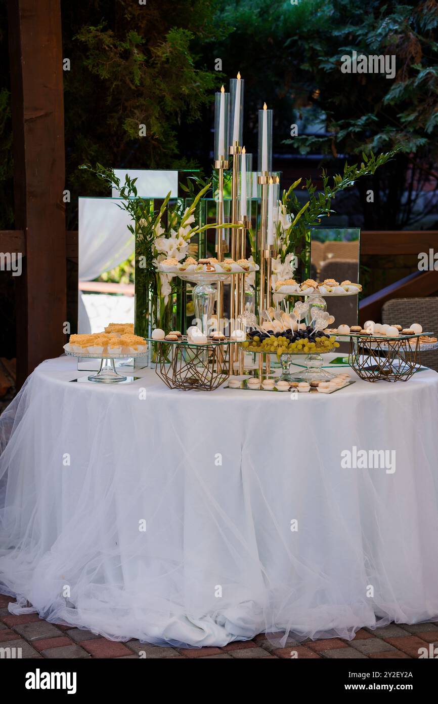 Elegant Outdoor Event Dessert Table with Candles and Floral Decorations ...