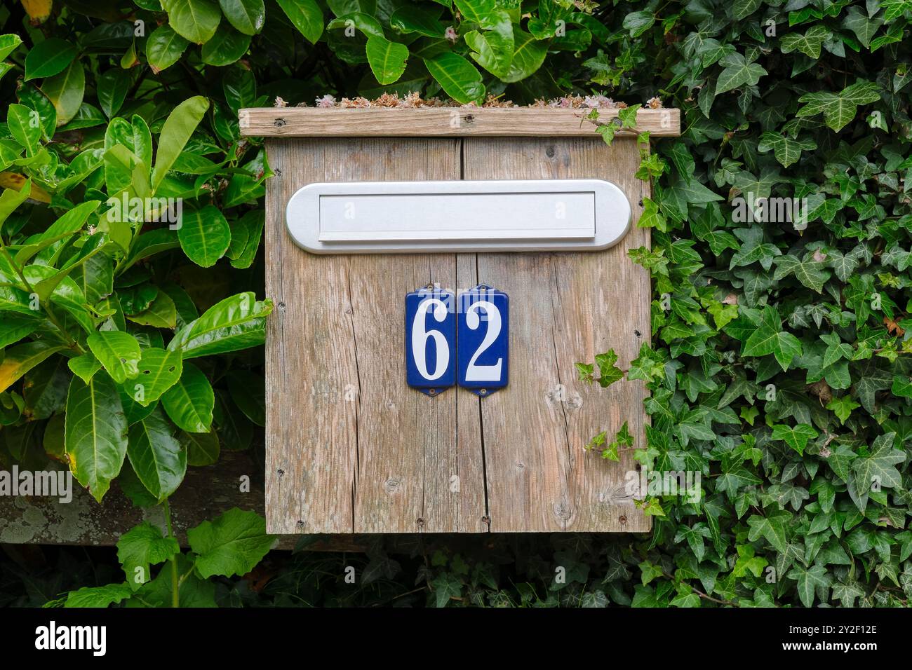 Old wooden unpainted mailbox with enamel number 62 in blue and white ...