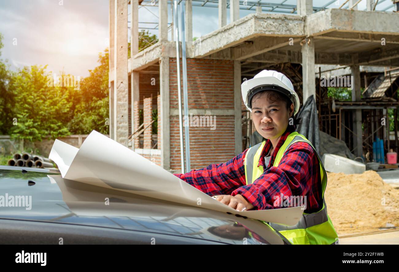 Engineers checking blueprint and planning project working outdoors building side on a worksite ...