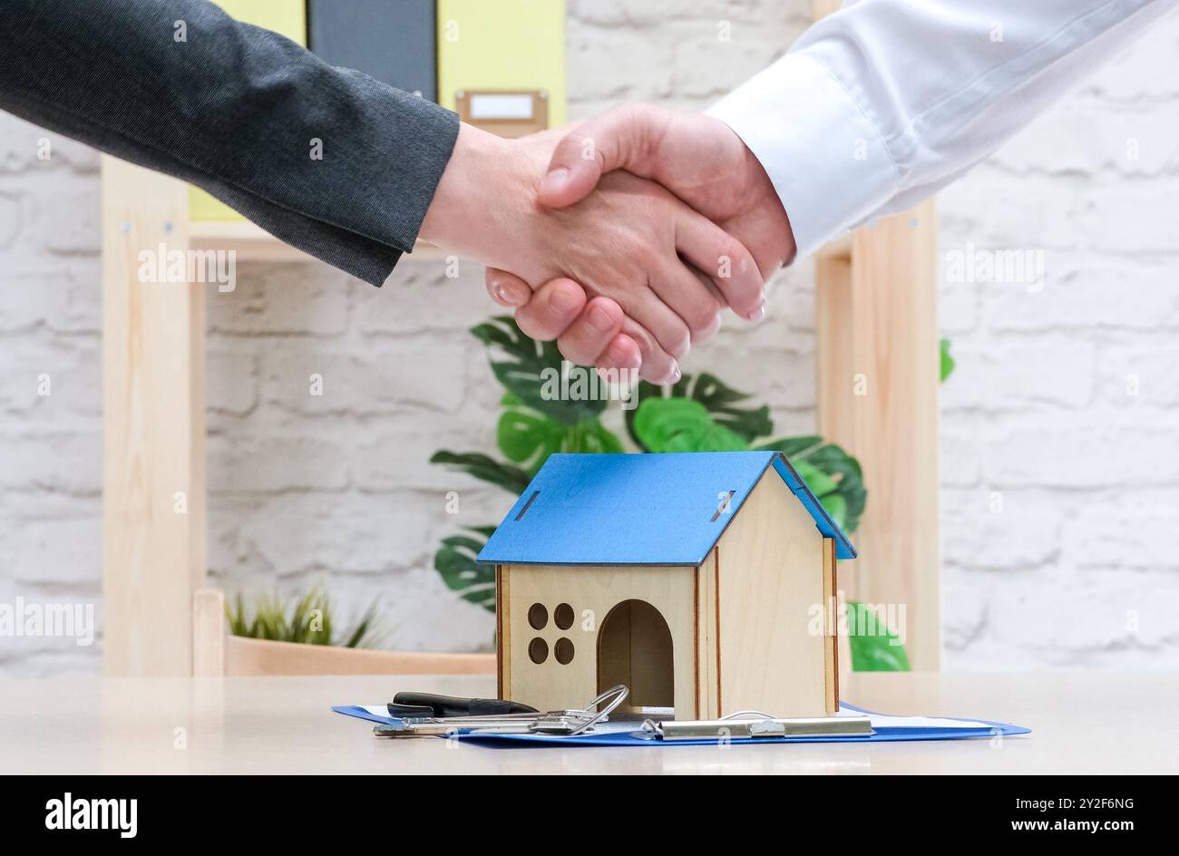 Handshake between seller and buyer of real estate. House model, keys ...