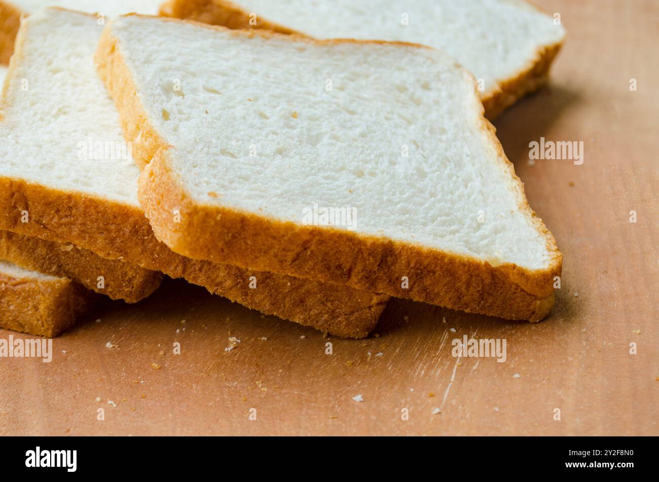 Fresh slices of bread displayed on wooden table. Breakfast concept ...