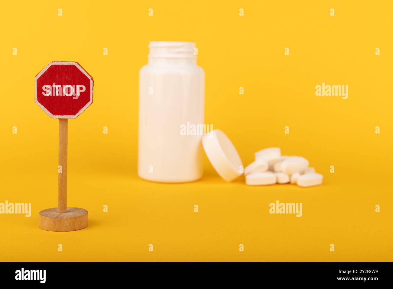 A white pill bottle spills its contents next to a toy stop sign on a ...