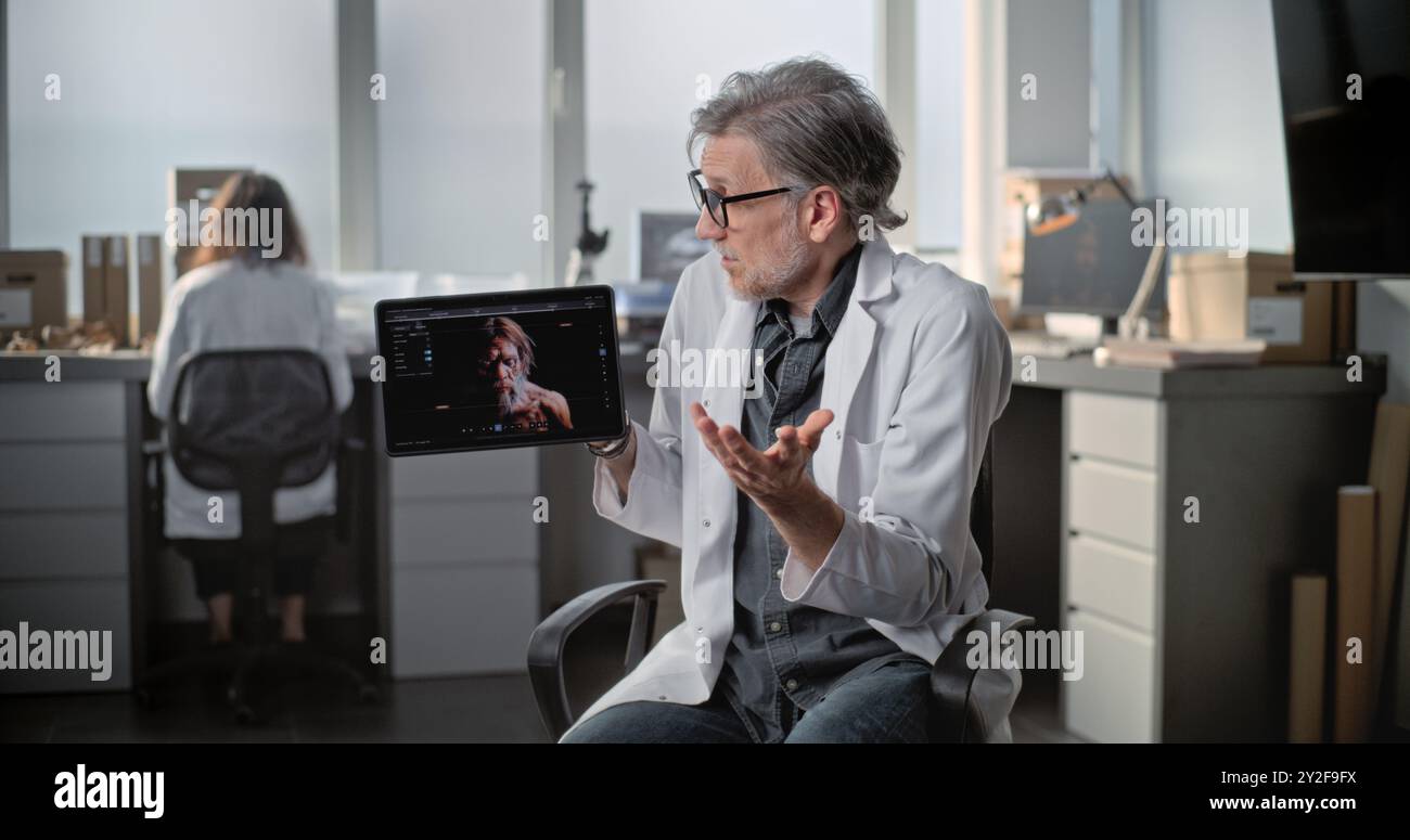 Mature scientist speaks to camera, shows 3D model of human head on ...