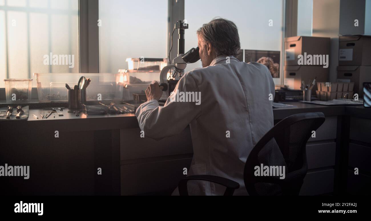 Mature microbiologist analyzes sample under hi-res stock photography ...