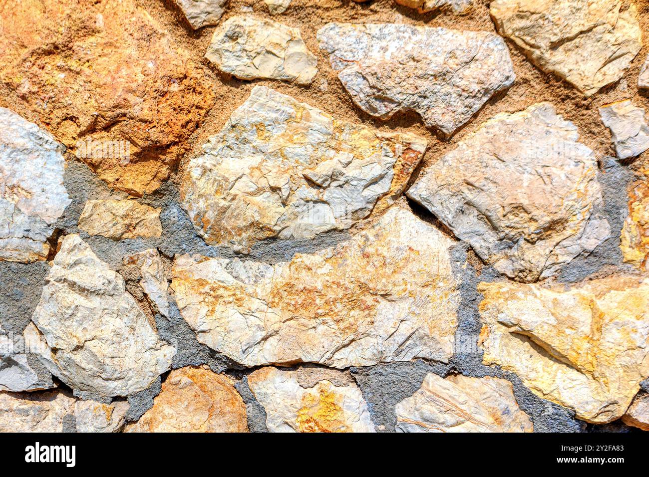 Textured wall composed of various sizes and shapes of rocks. Natural ...