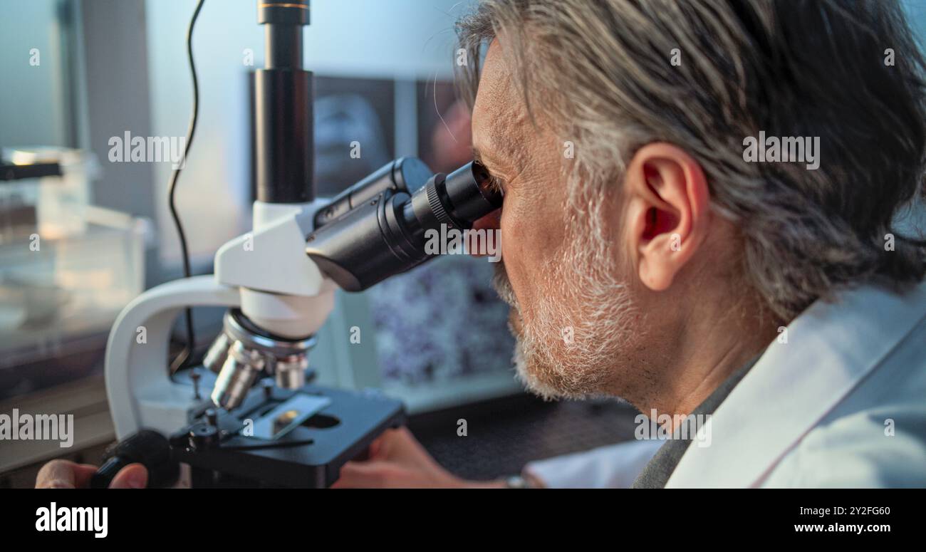 Mature microbiologist conducts fossil analysis under microscope, looks ...