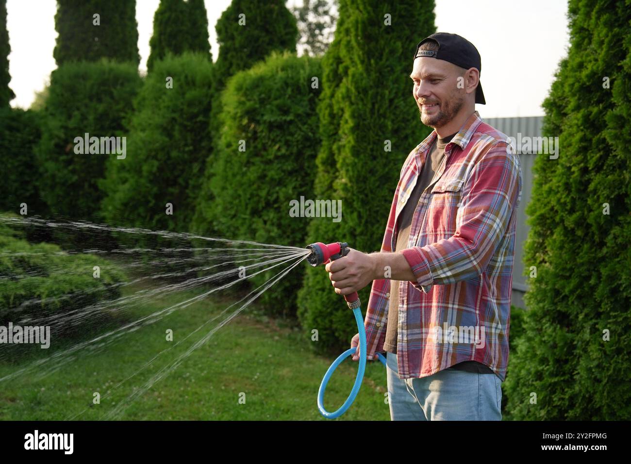 Man watering lawn with hose in backyard Stock Photo - Alamy