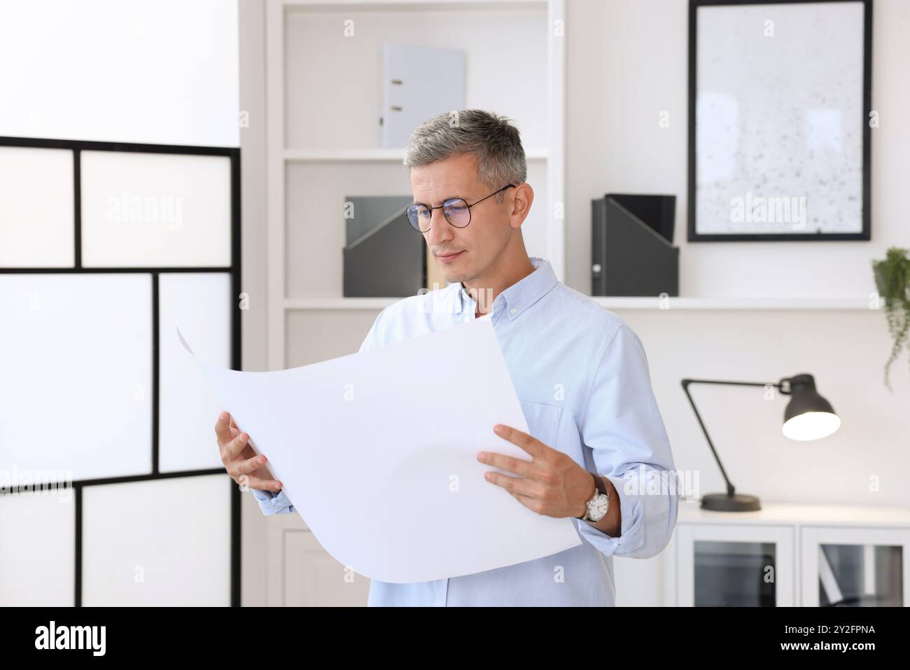 Architect holding paper sheet with engineering drawing in office Stock ...