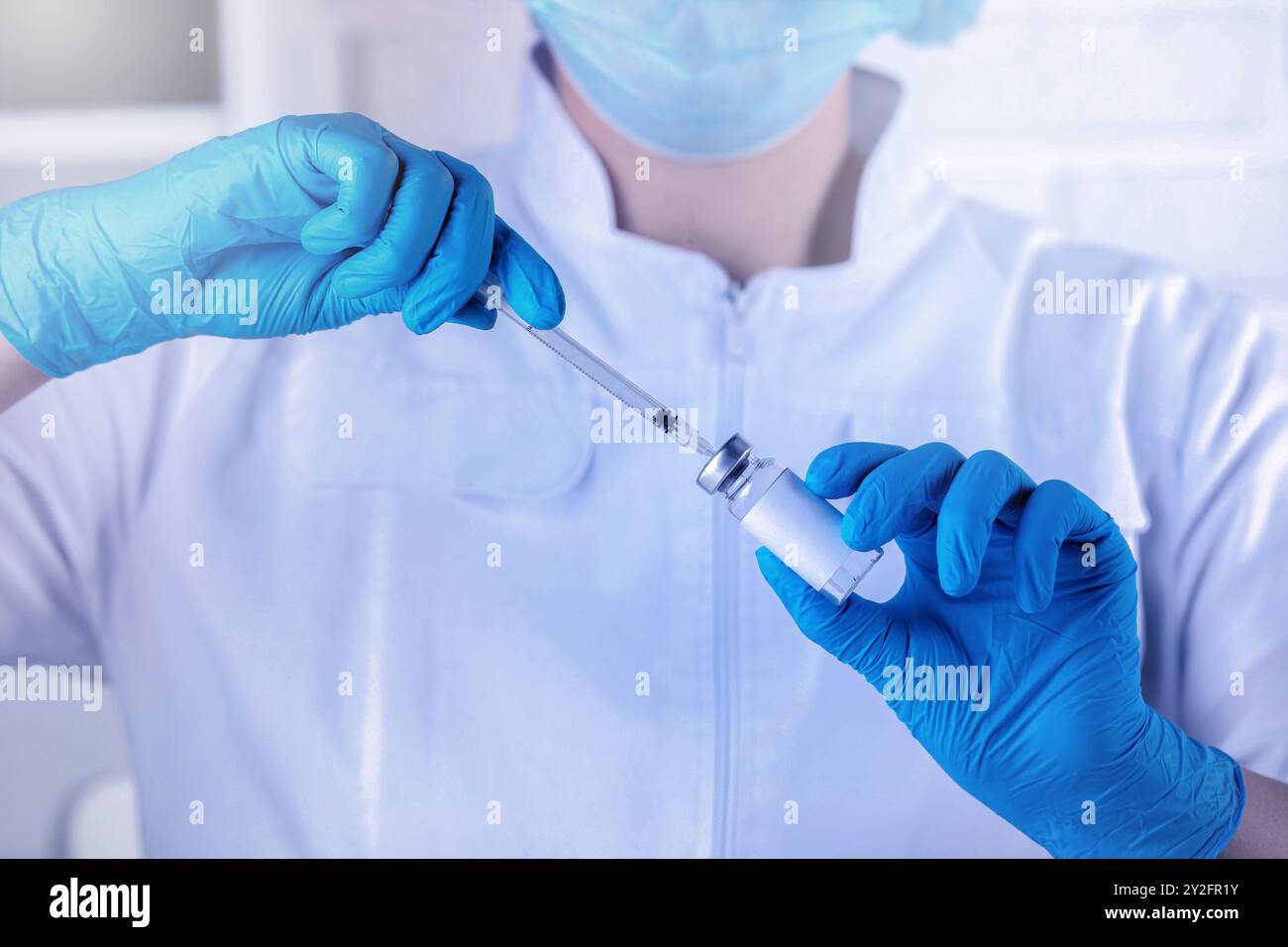 Nurse filling syringe with medication from glass vial in hospital ...