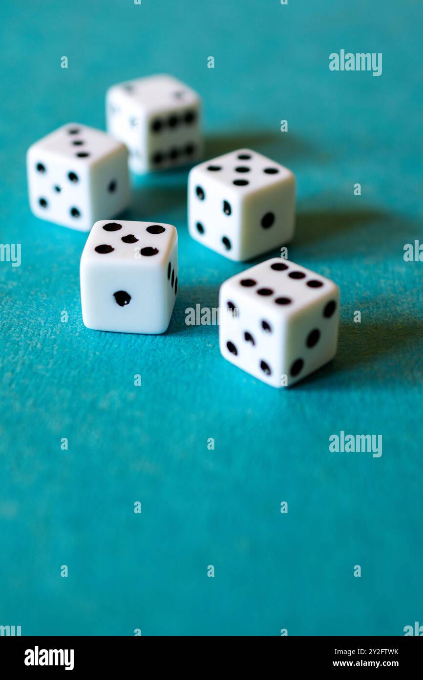 Five dice on a teal background with side lighting Stock Photo - Alamy