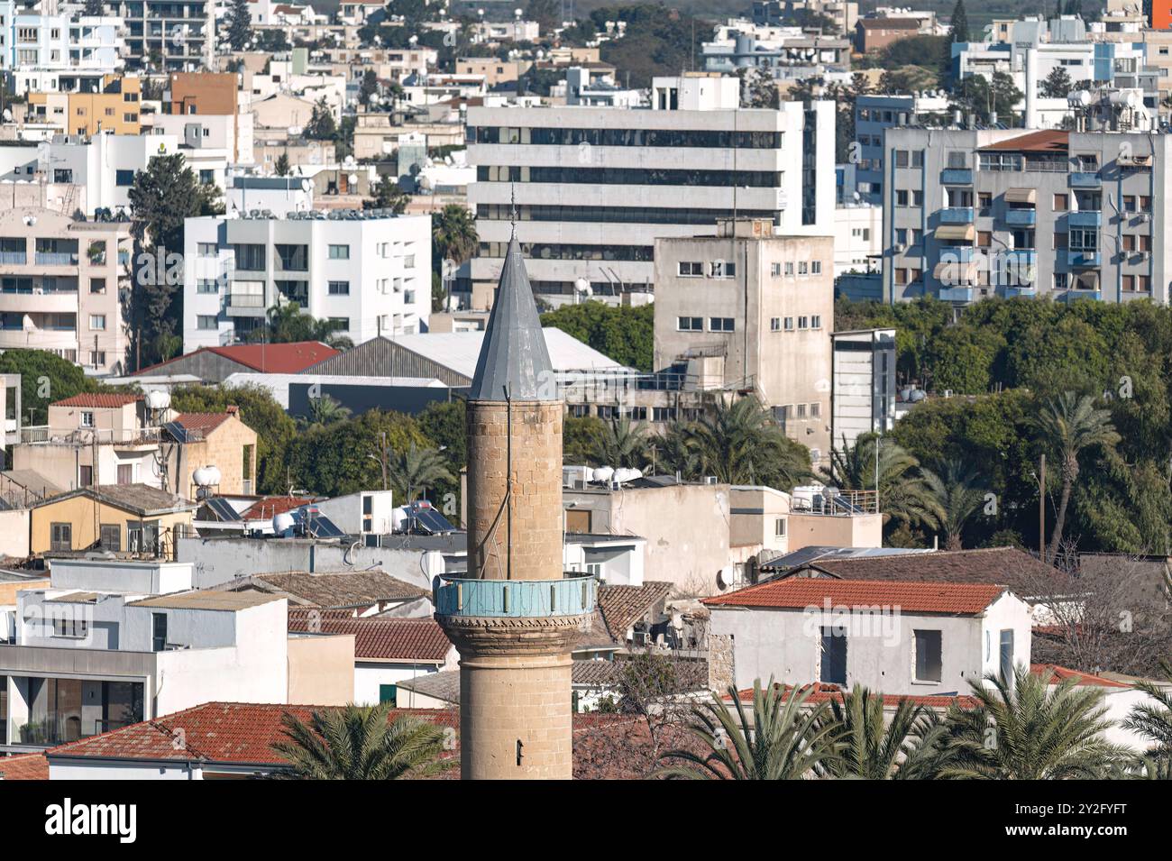 Minaret of Bayraktar Mosque is standing out from a skyline filled with buildings and palm trees ...