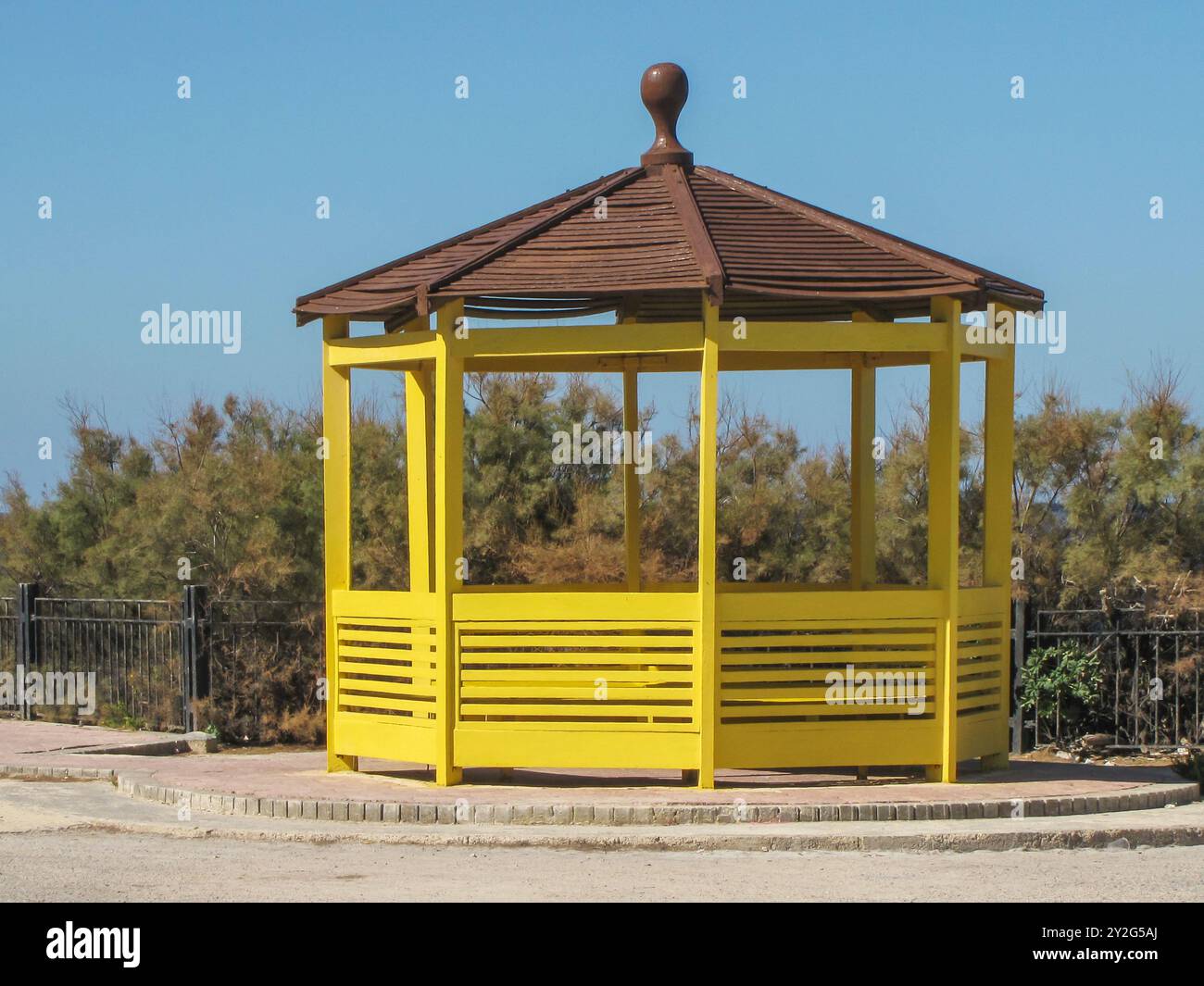Wooden gazebo in nature with clear blue sky and vibrant yellow ...