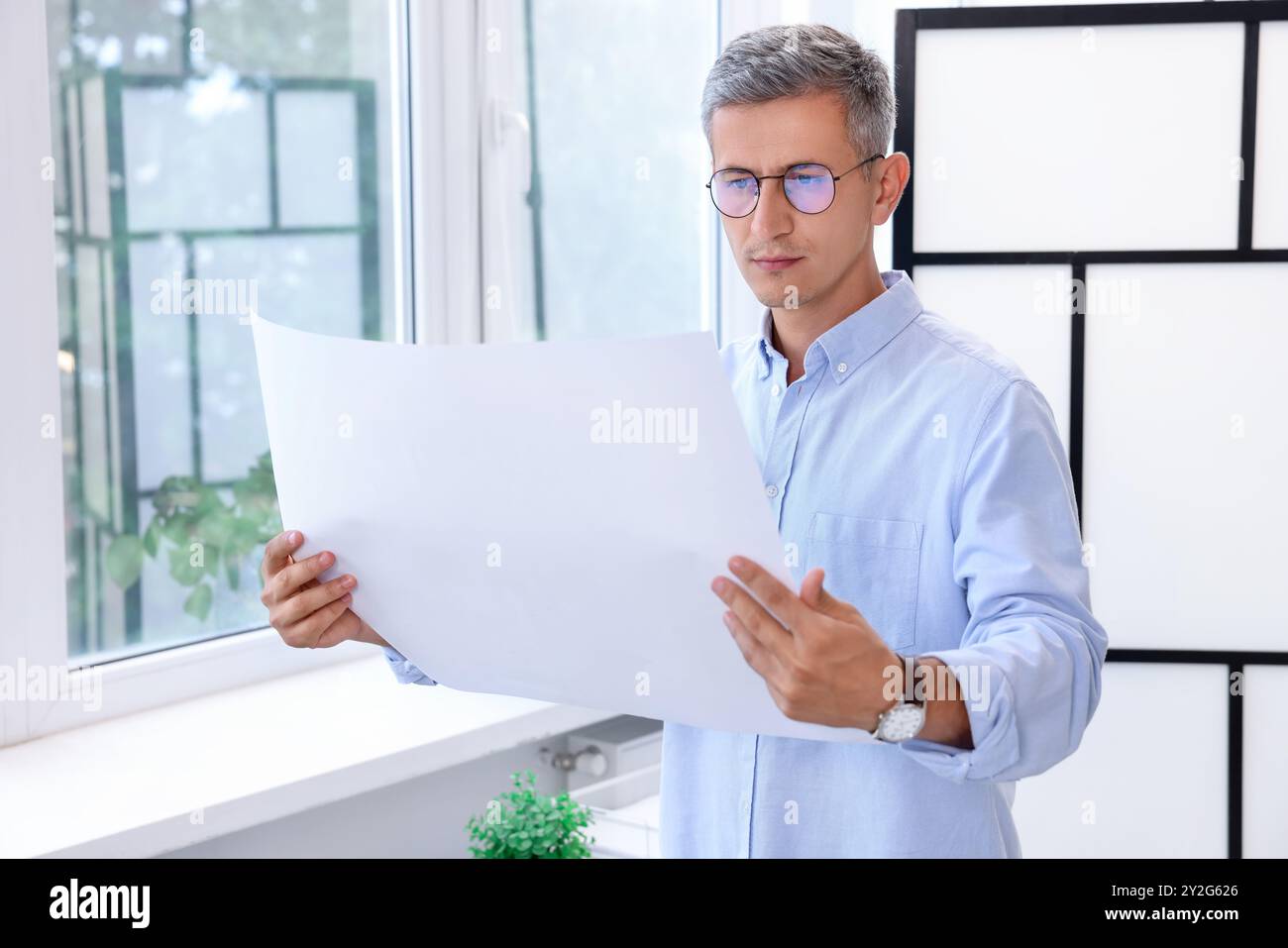 Architect holding paper sheet with engineering drawing in office Stock ...