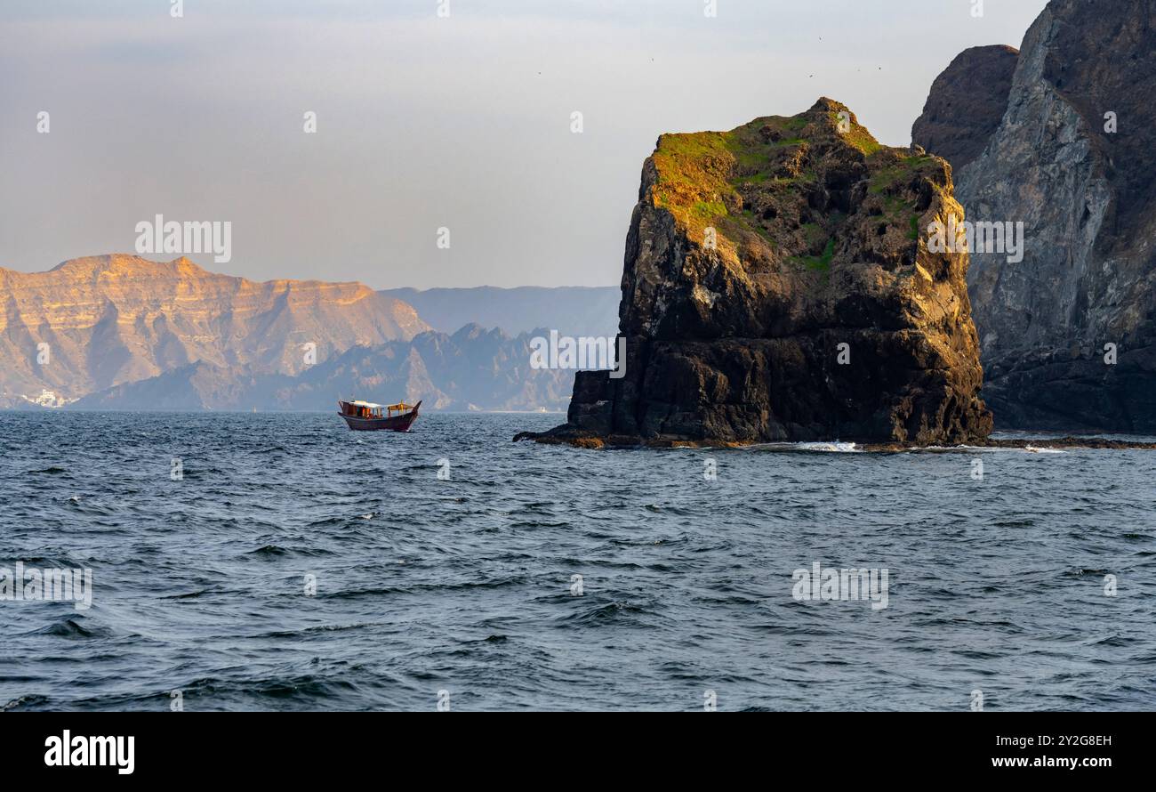 Boat by the rock formations in the Gulf of Oman at sunset Stock Photo ...
