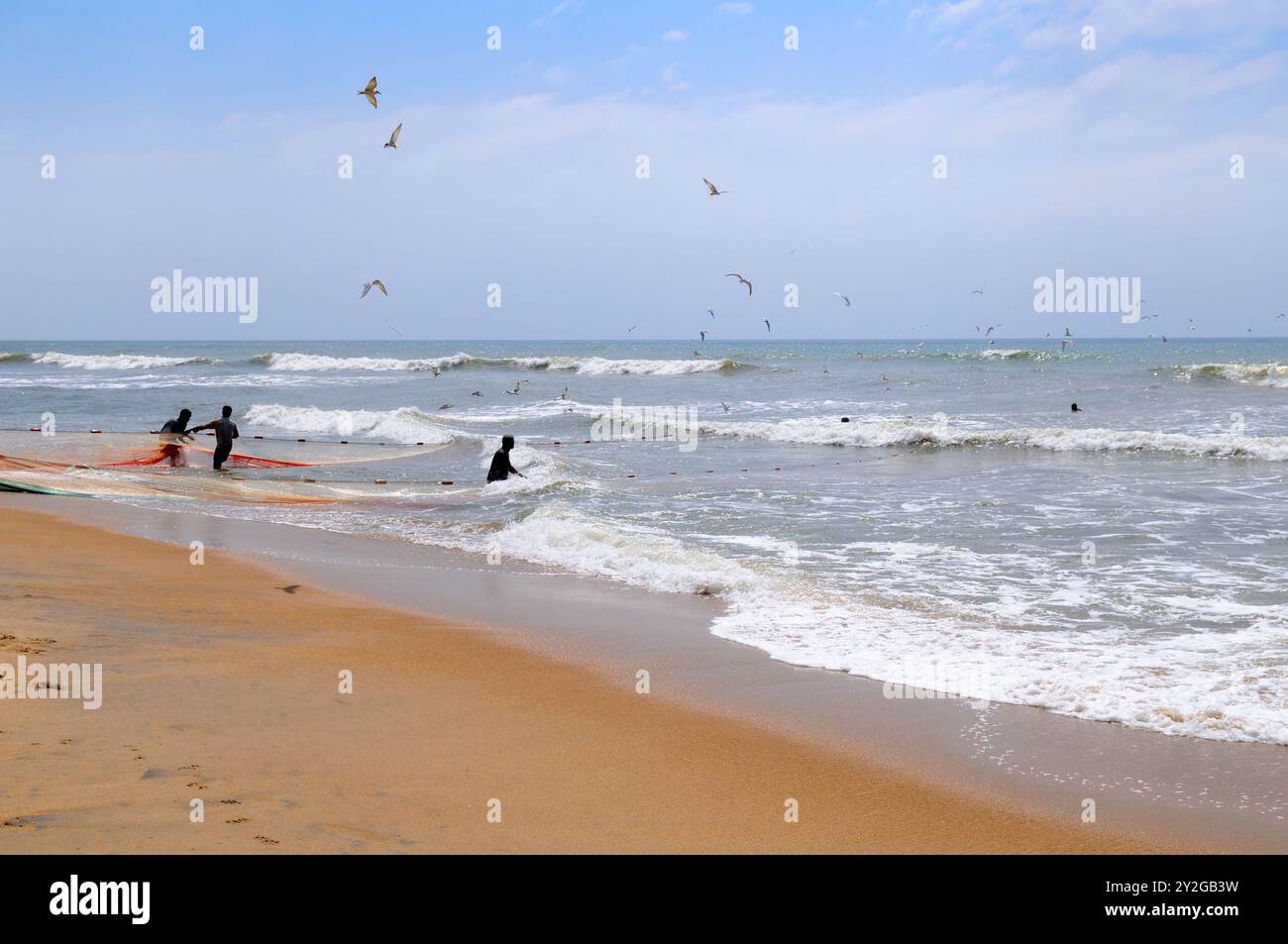 group of men helping fishermen to pull over large fishing net from ...