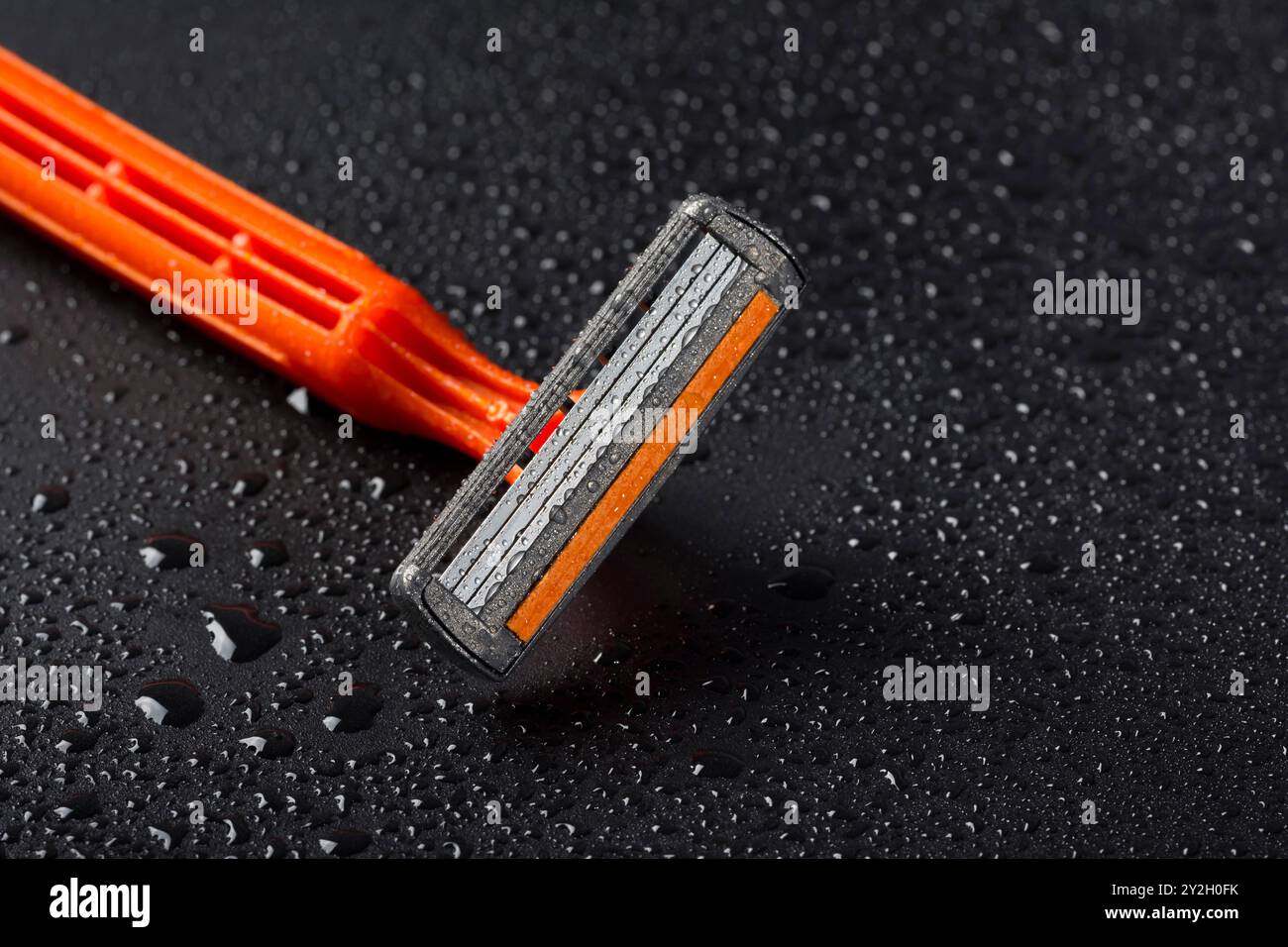 Razor with drops of water on a black background. Close-up. New razor ...