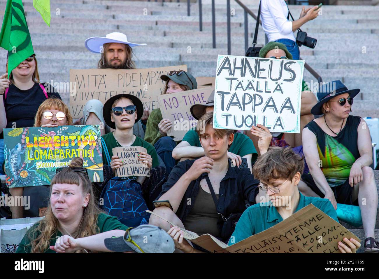 Protesters with handwritten cardboard signs sitting on Parliament House ...