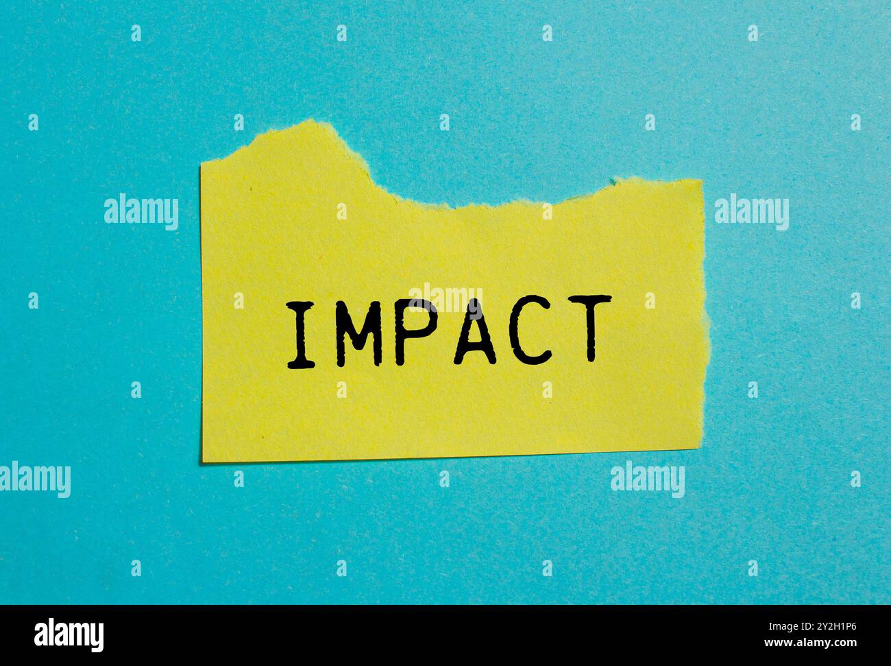 Impact word written on ripped torn yellow paper with blue background ...