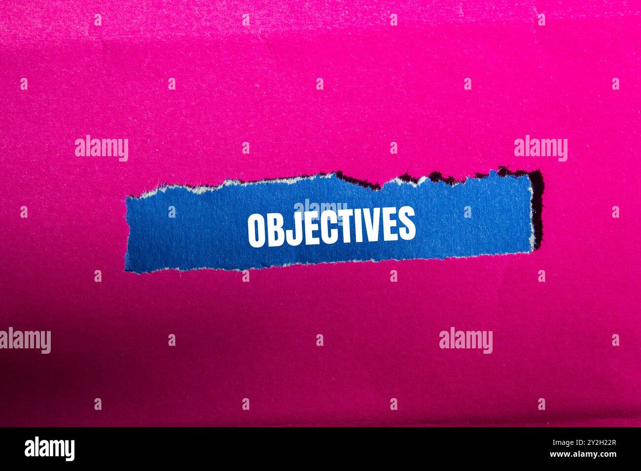 Objectives message written on ripped torn blue paper piece with pink ...