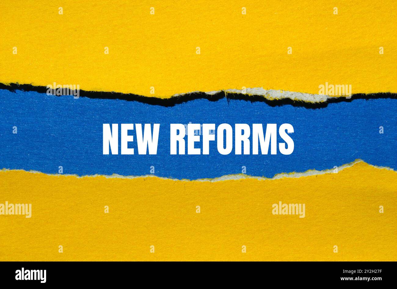 New reforms message written on ripped torn yellow paper with blue ...