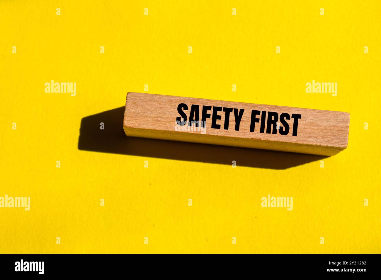 Safety first message written on wooden block with yellow background ...