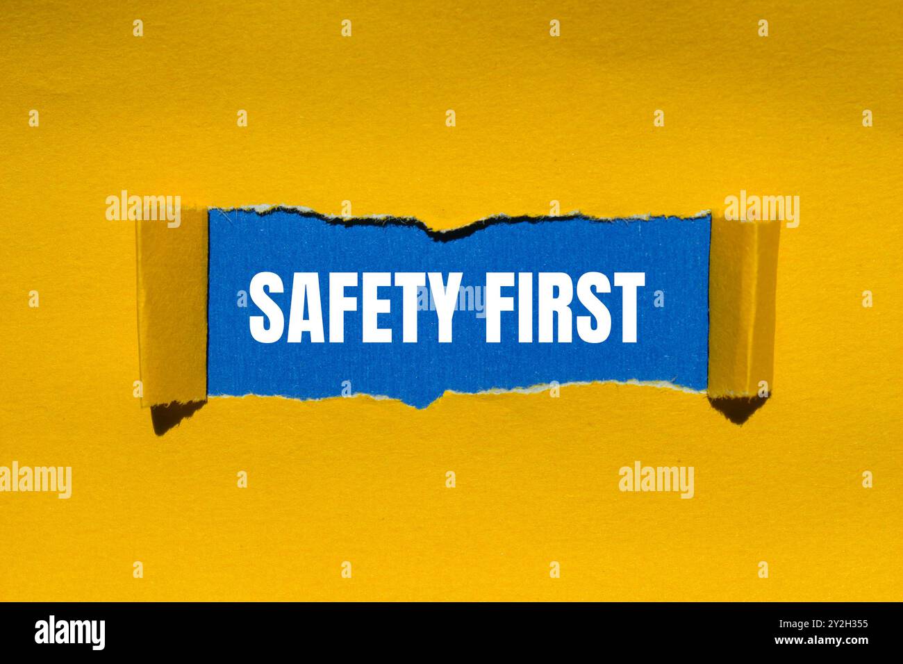 Safety first message written on ripped torn yellow paper with blue ...