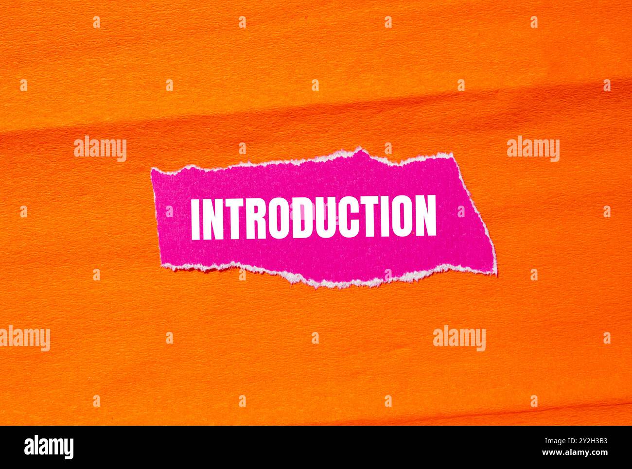 Introduction message written on ripped torn pink paper with orange ...