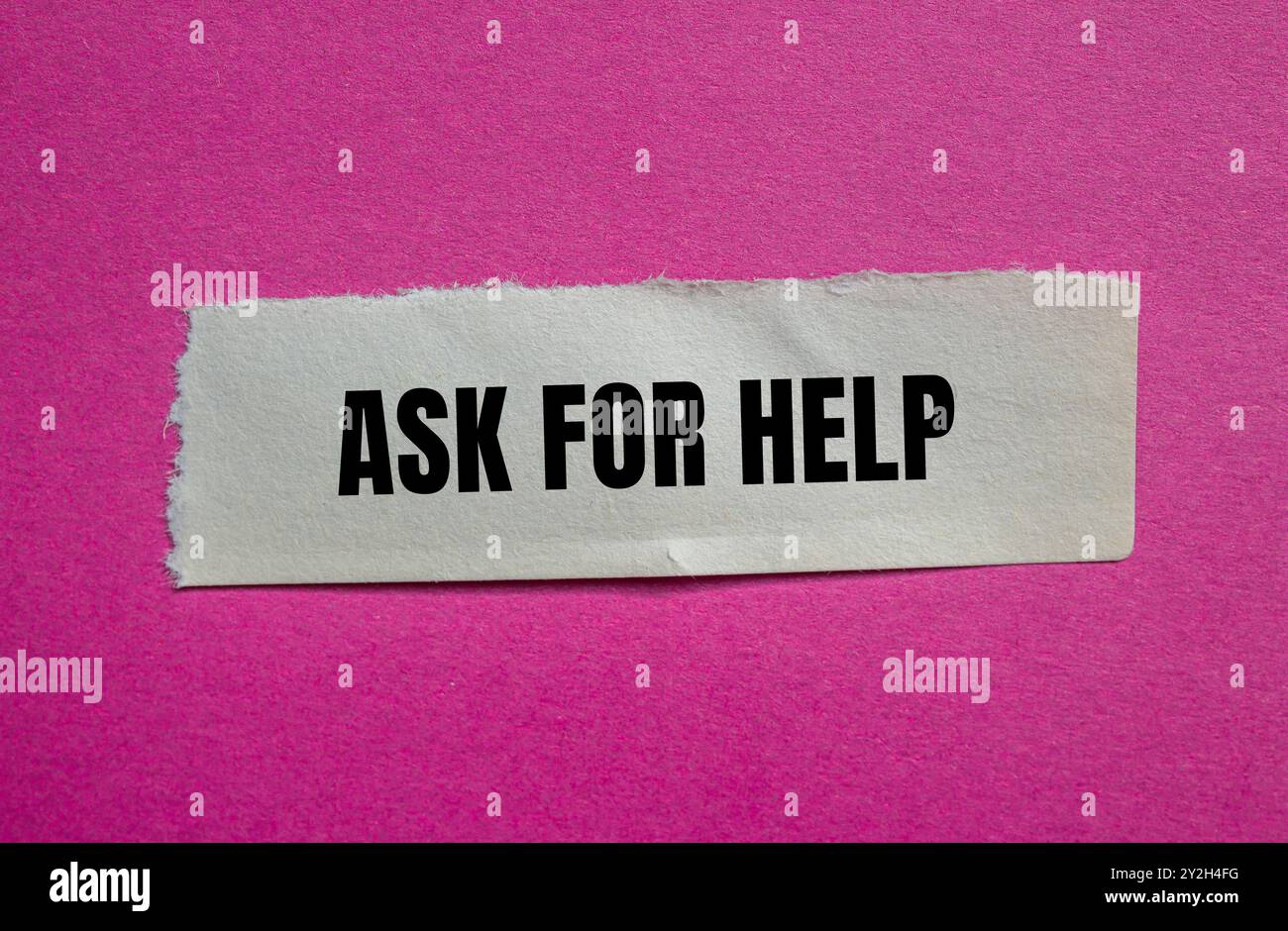 Ask for help message written on ripped torn paper piece with pink ...