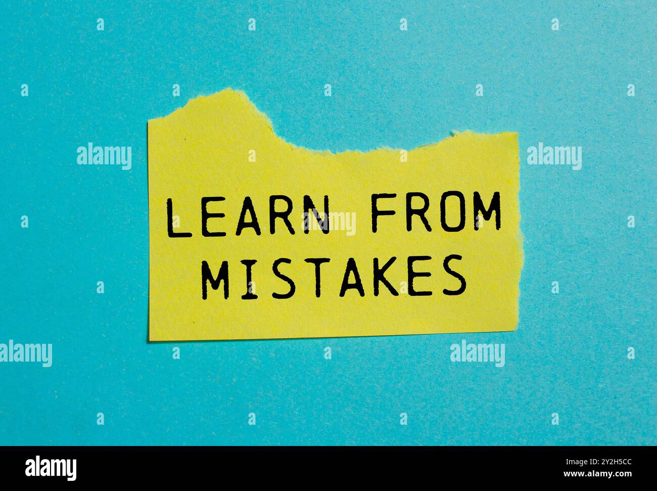 Learn from mistakes message written on ripped torn yellow paper with blue background. Conceptual ...
