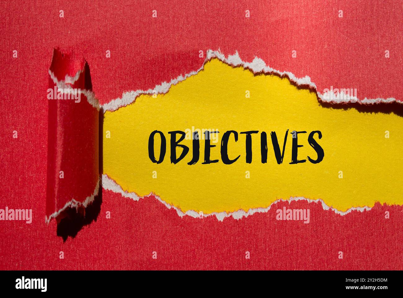 Objectives message written on ripped torn red paper with yellow background. Conceptual ...