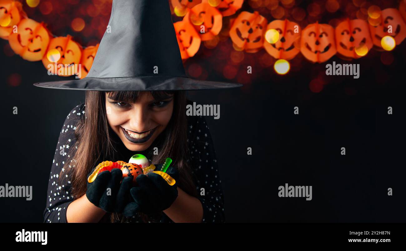 Pretty and funny little girl dressed as a witch with her hands full of ...