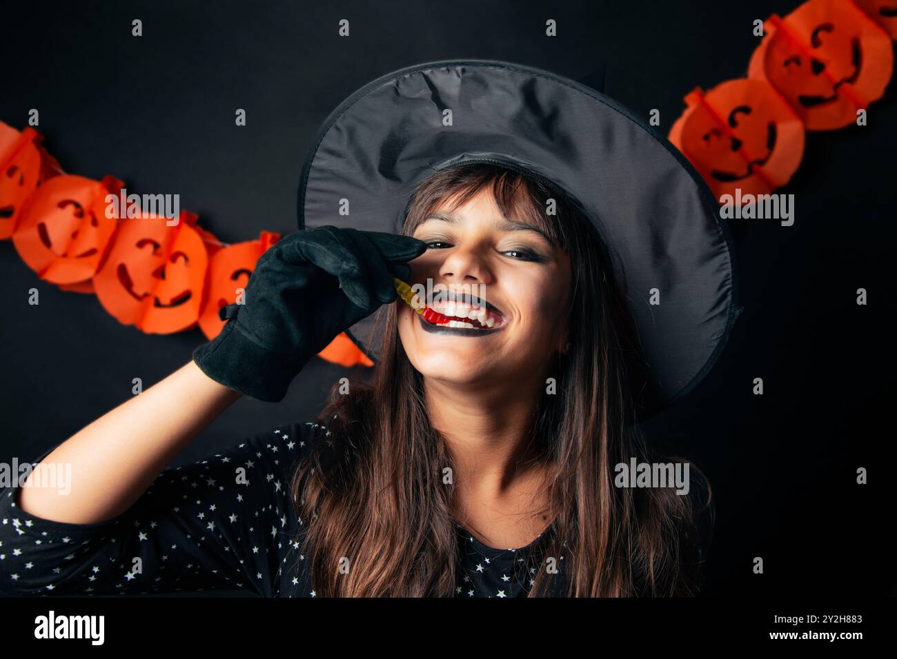 Pretty and funny little girl dressed as a witch eating a worm shaped ...