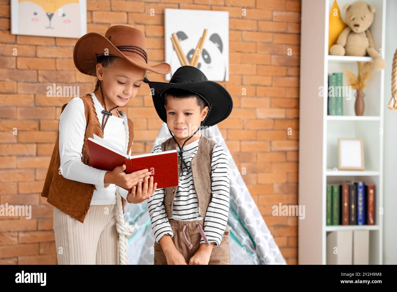 Cute little cowboys with adventure book at home Stock Photo - Alamy
