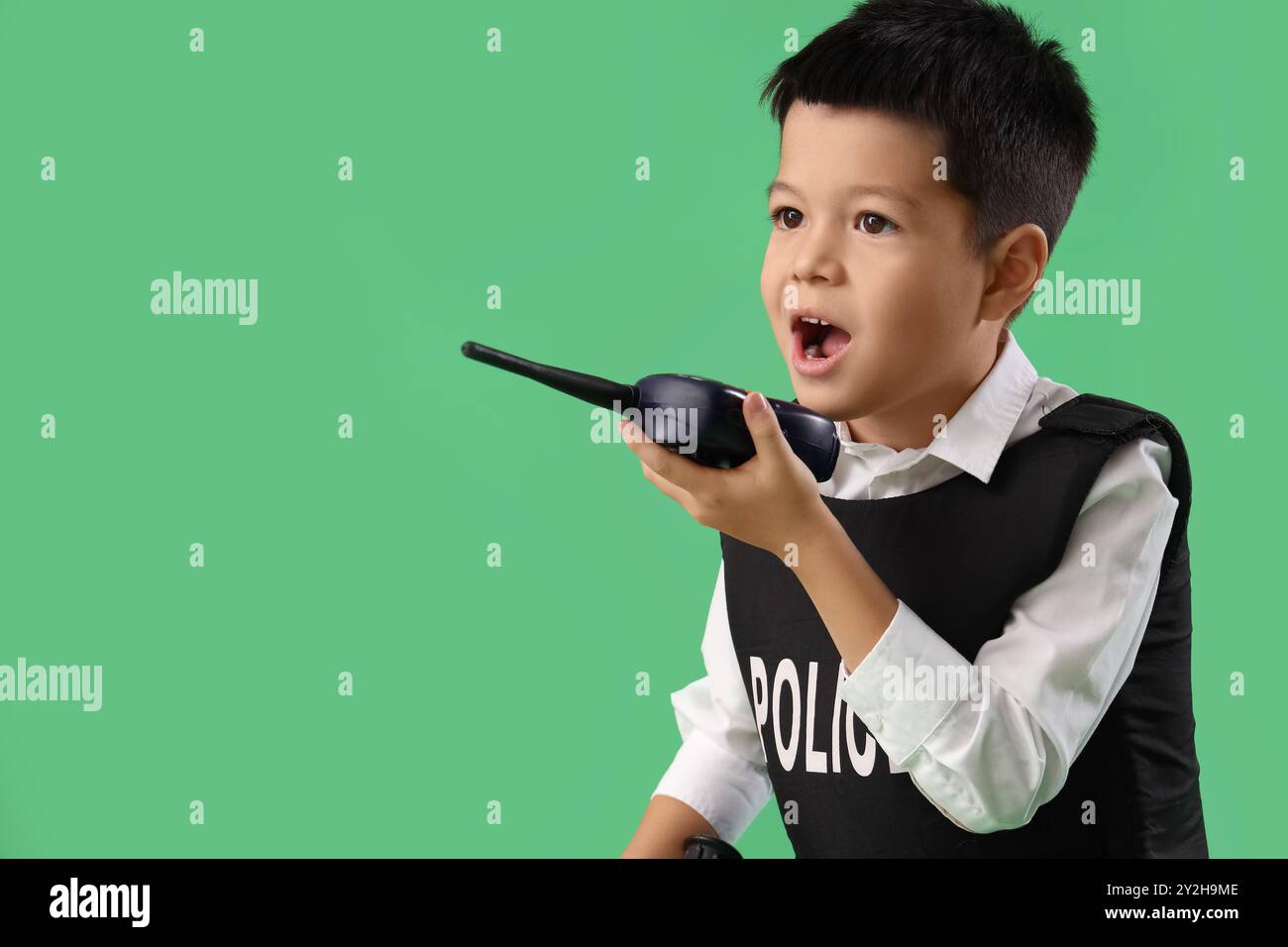 Cute little police officer with radio transmitter on green background ...