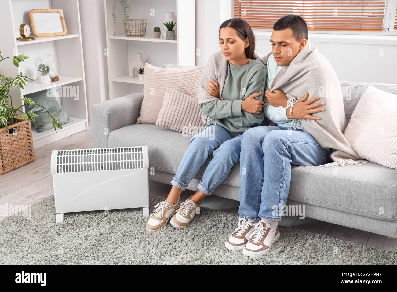 Frozen young couple with plaid warming near radiator at home Stock ...