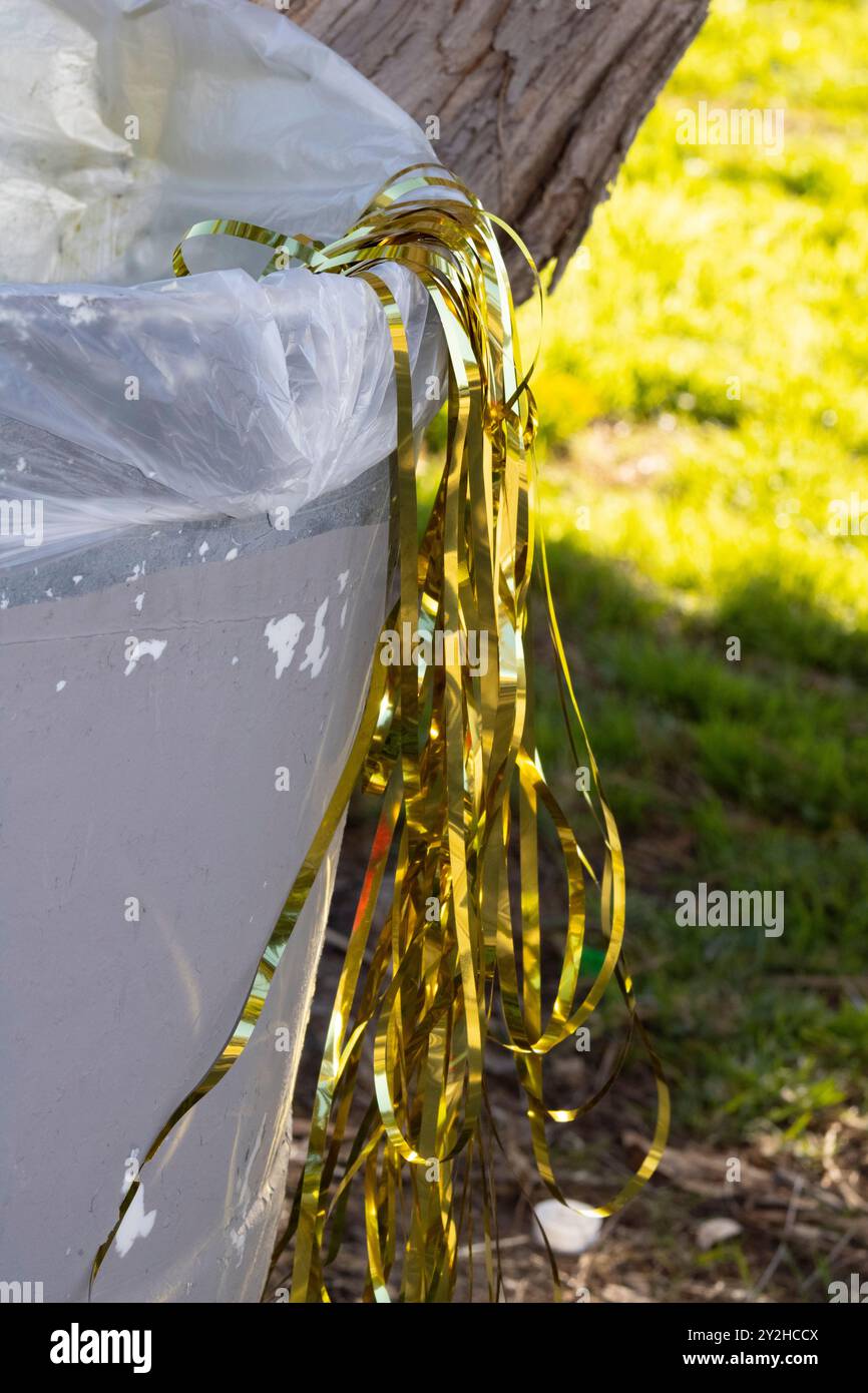 gold celebratory party streamers thrown away in outdoor trash can Stock ...