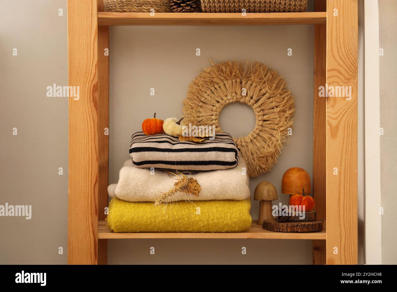 Shelving unit with stacks of stylish clothes and autumn decorations ...