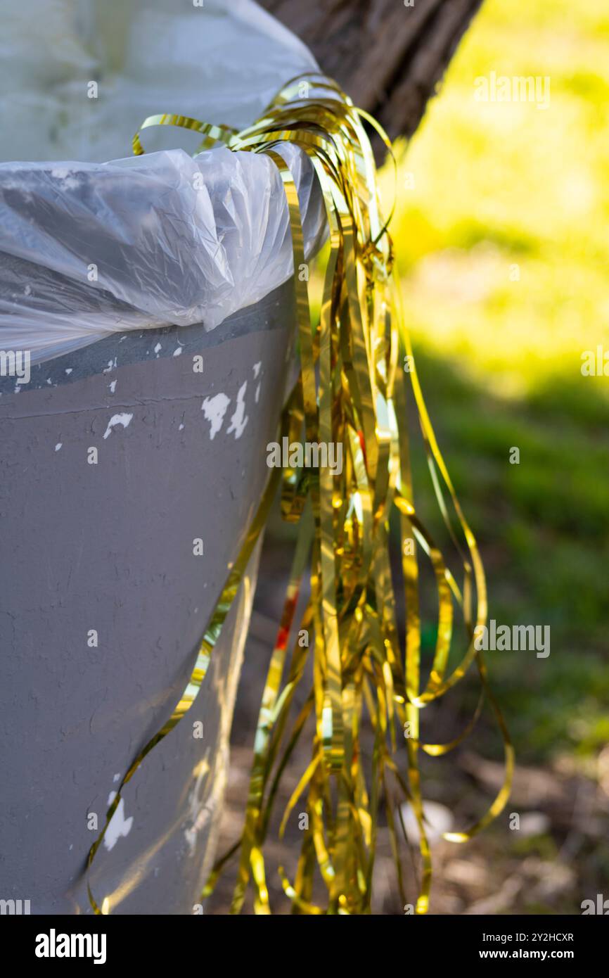 gold celebratory party streamers thrown away in outdoor trash can Stock ...