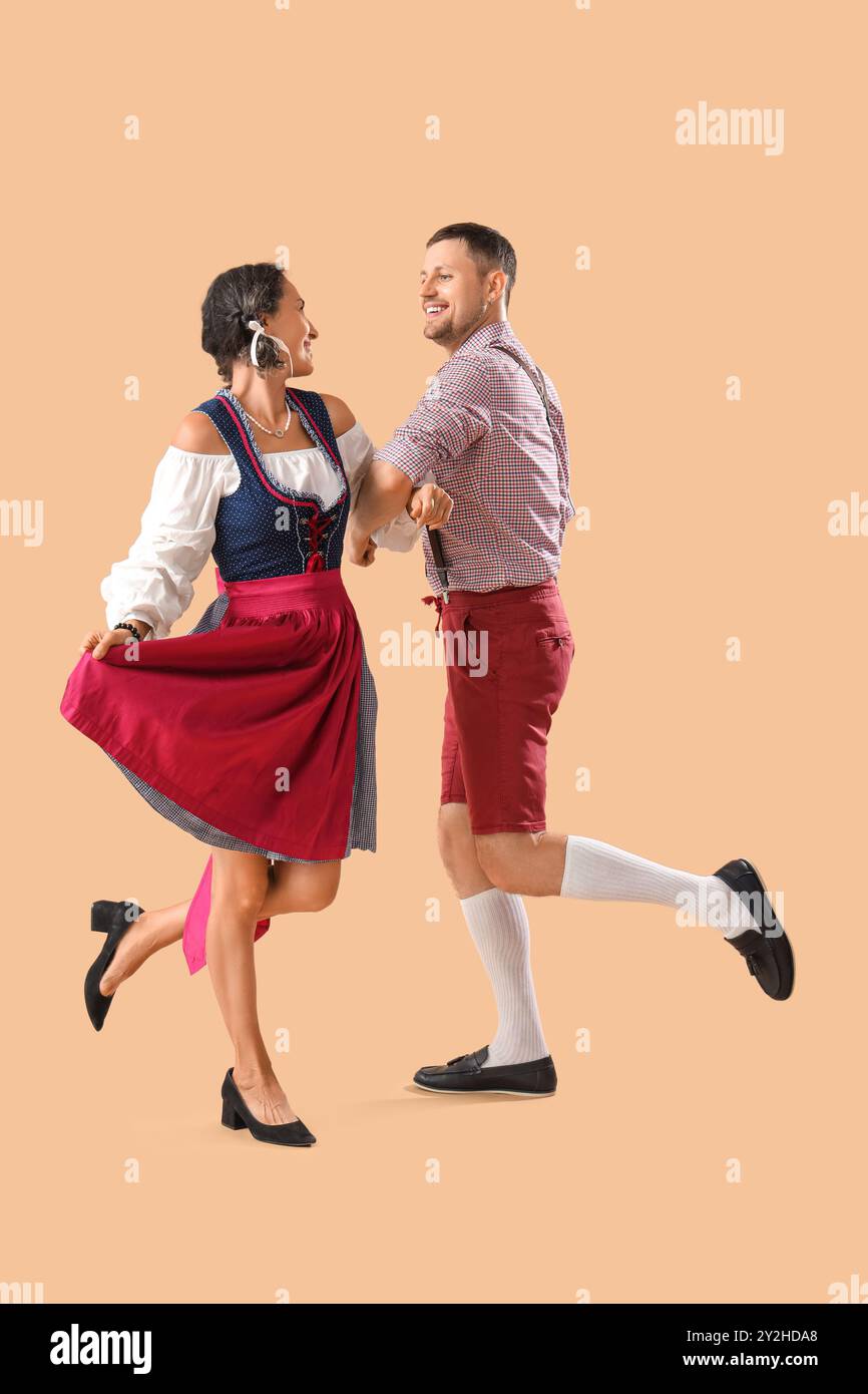Happy mature waiters in traditional German clothes dancing on beige ...