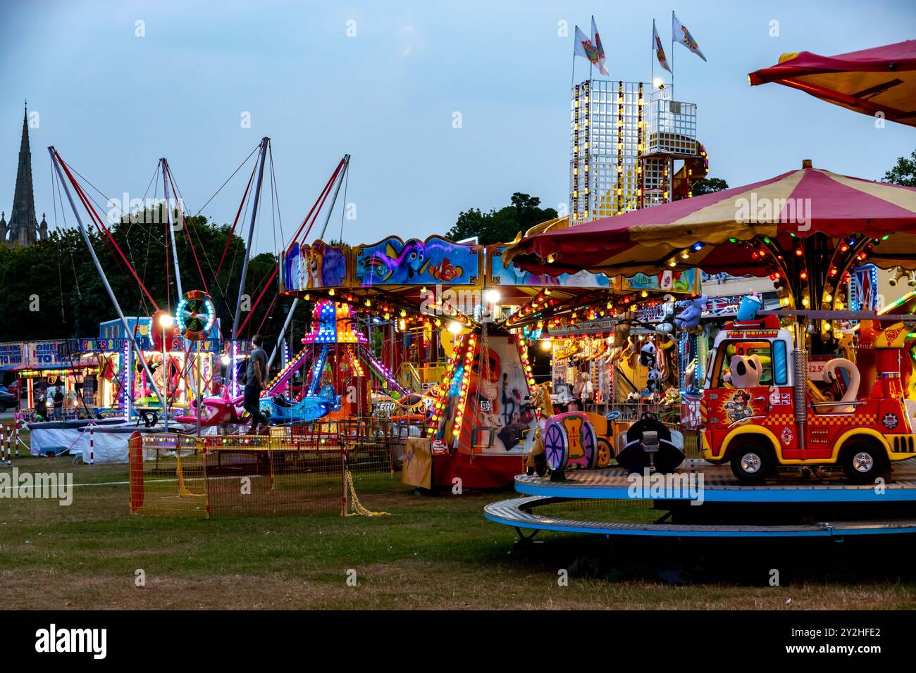 Dusk at a travelling funfair with illuminated rides, games and ...