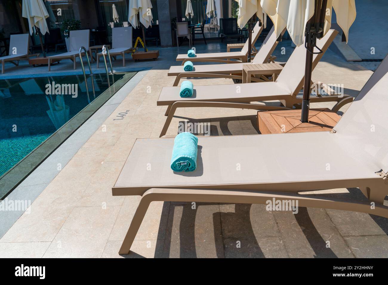 Swimming pool with sun loungers, parasols and towels in a row Stock ...