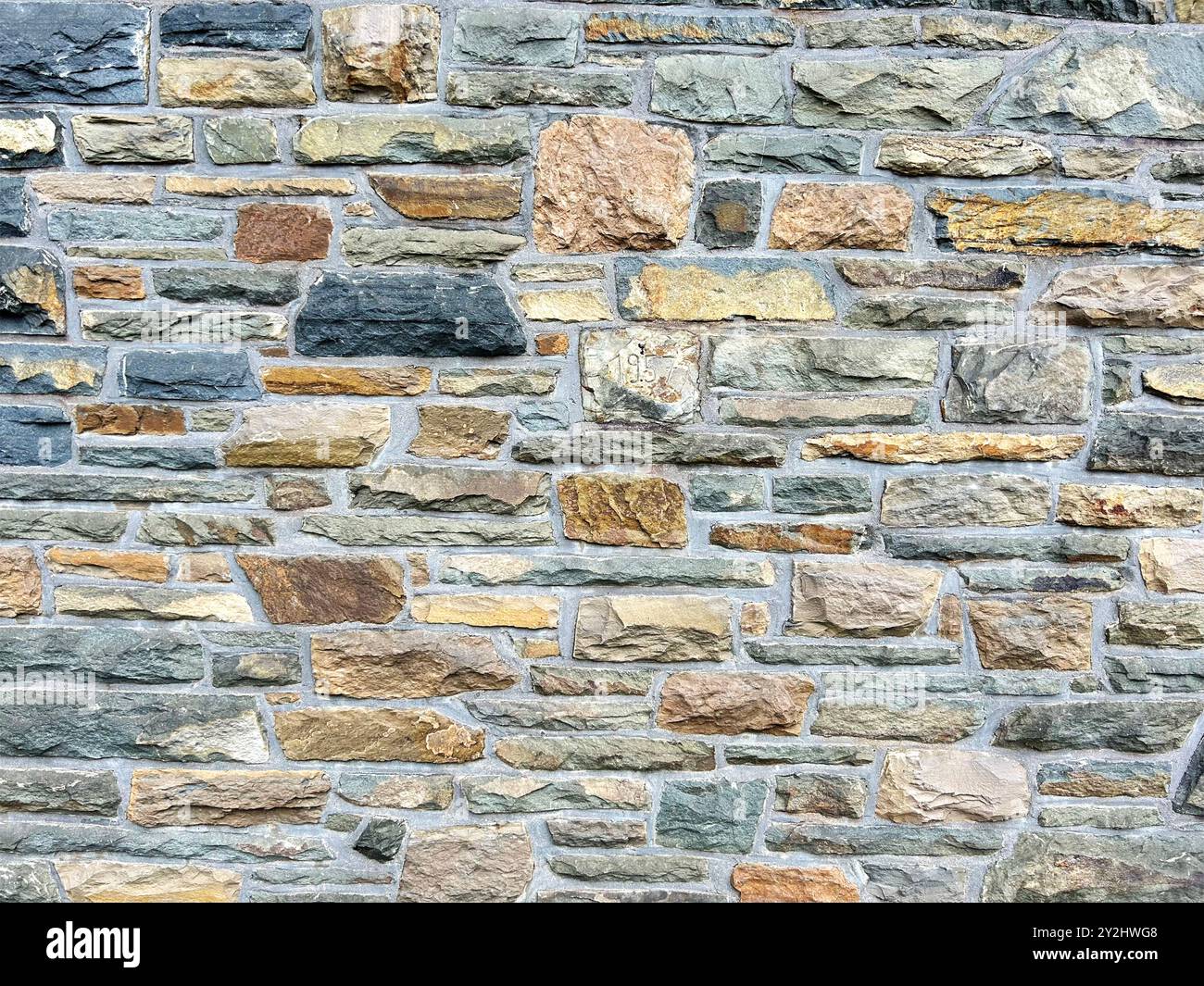 A fascinating, well-kept stone wall from 1957 made of different colored ...