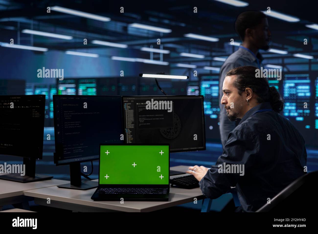 Admin in data center using isolated screen laptop to check for server performance issues. IT ...