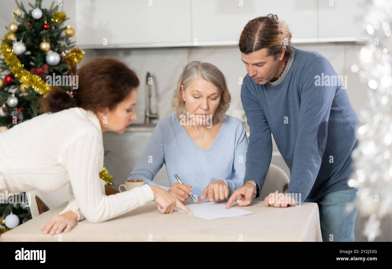 Man and woman help elderly mother make will and fill out document ...