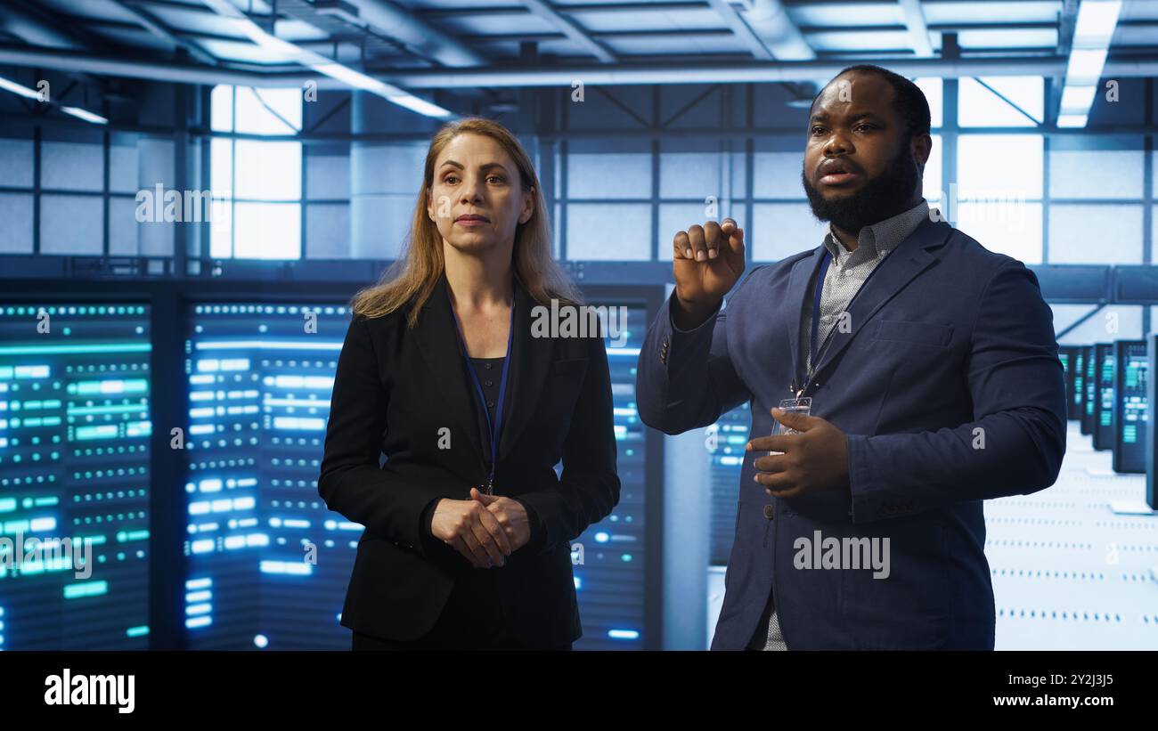 Teamworking technicians in high tech data center workspace looking at hologram visualization ...