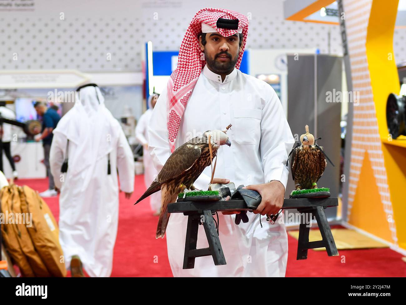 A Qatari exhibitor carries falcons during the 8th edition of the Katara ...