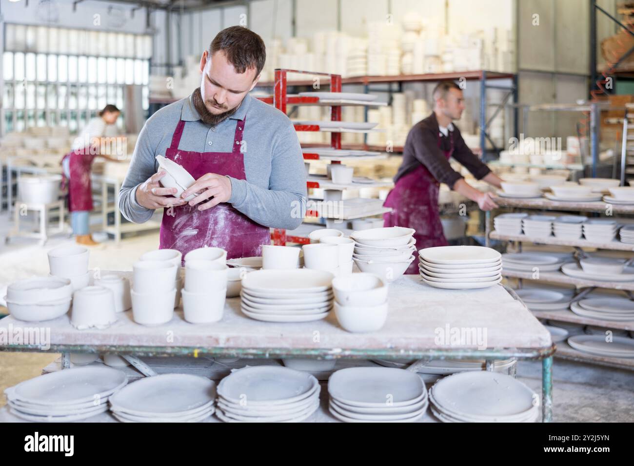 Pottery expert inspecting handmade plate in artisanal ceramics studio ...