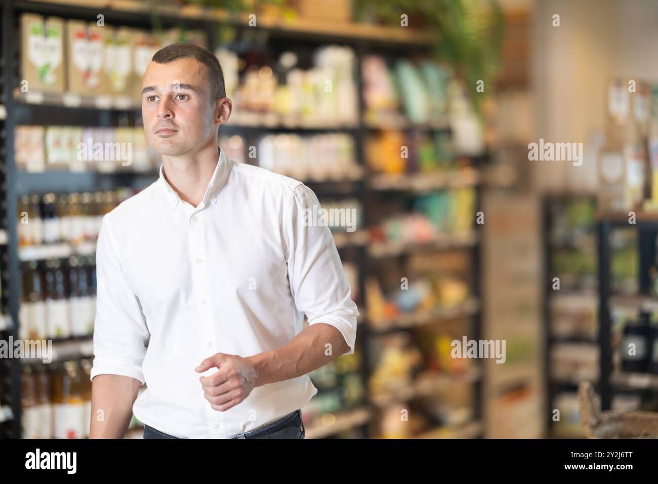 Interested young man walking through organic store aisle Stock Photo ...